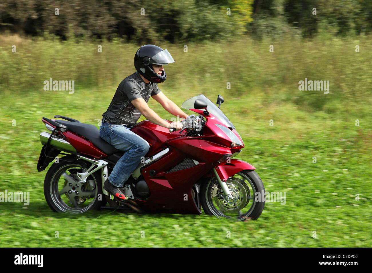 motorcyclist riding on meadow Stock Photo - Alamy