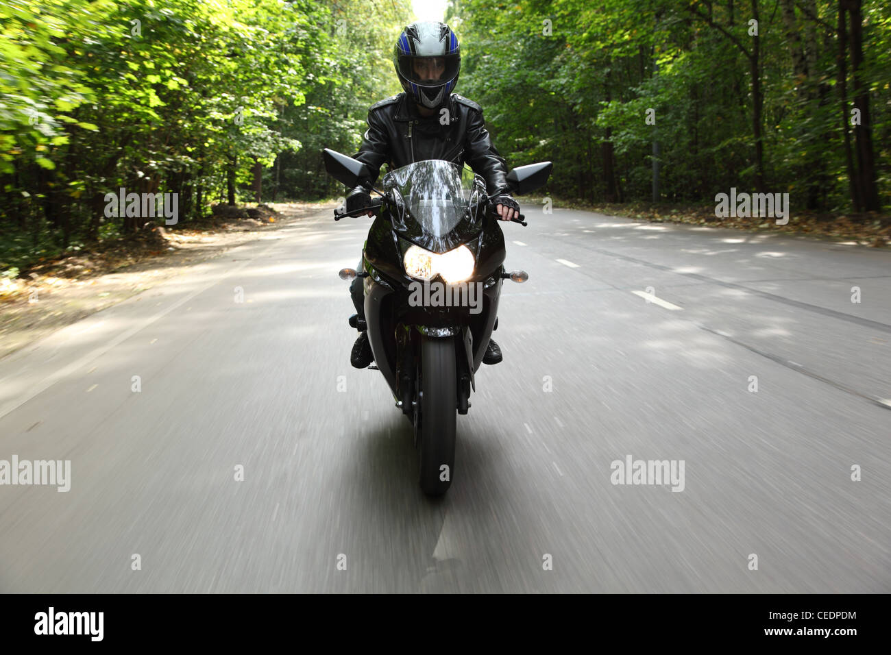 motorcyclist goes on road, front view Stock Photo - Alamy