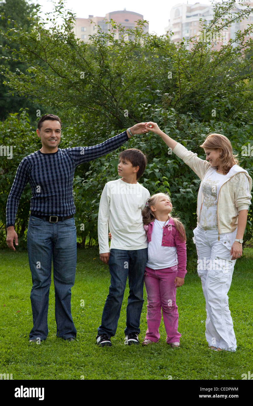 parents playing with children in park, making house, full body Stock ...