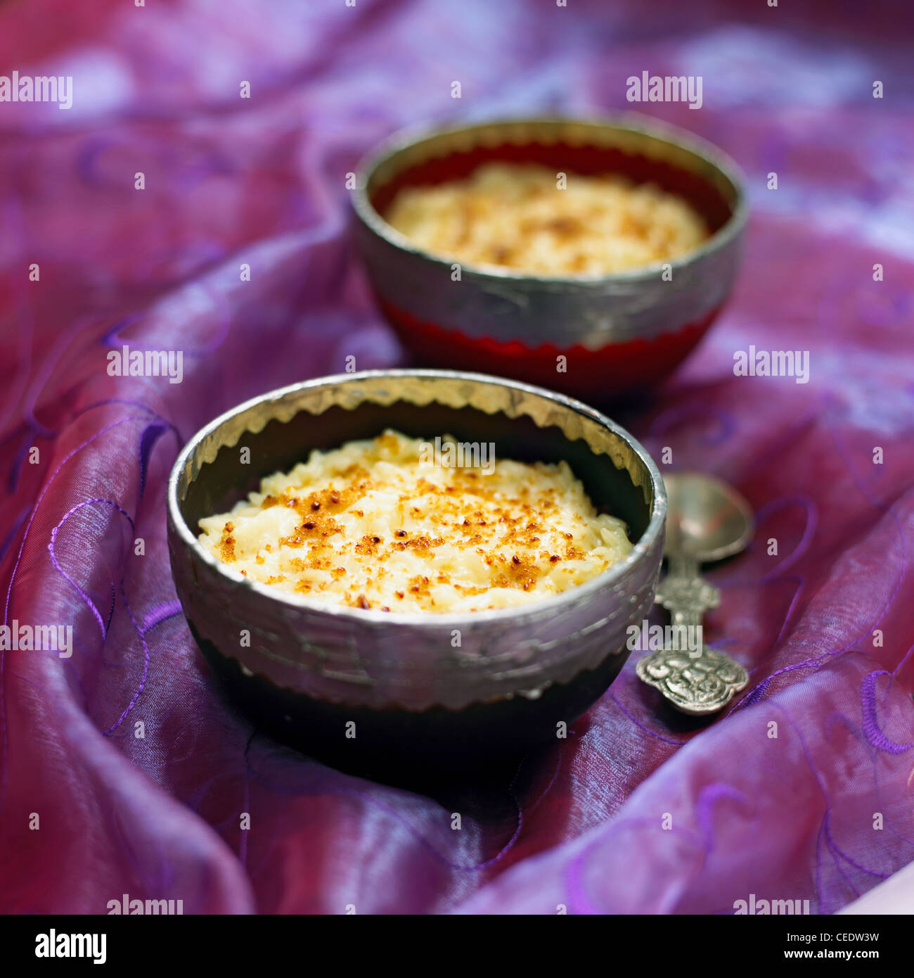 Two Indian Basmati rice puddings in bowls with a silver spoon on an ...