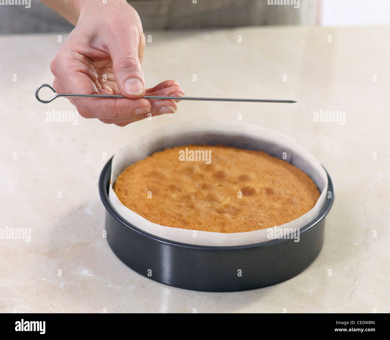 Testing Victoria sponge cake with skewer Stock Photo - Alamy