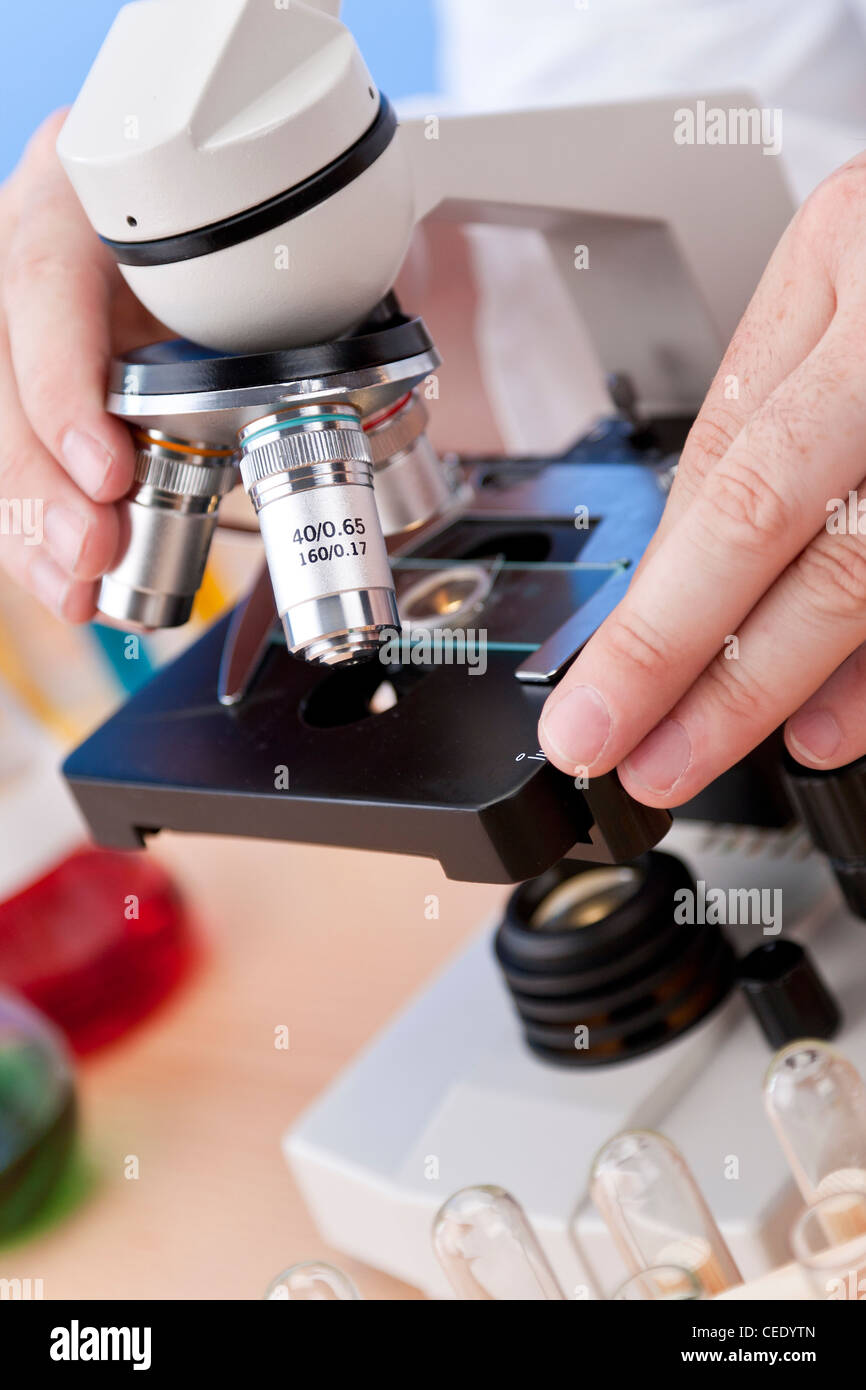 A medical or scientific researcher using a microscope in a laboratory ...