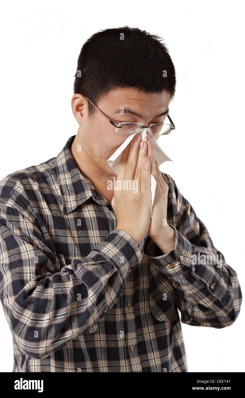 Young man with a cold blowing nose on tissue Stock Photo - Alamy