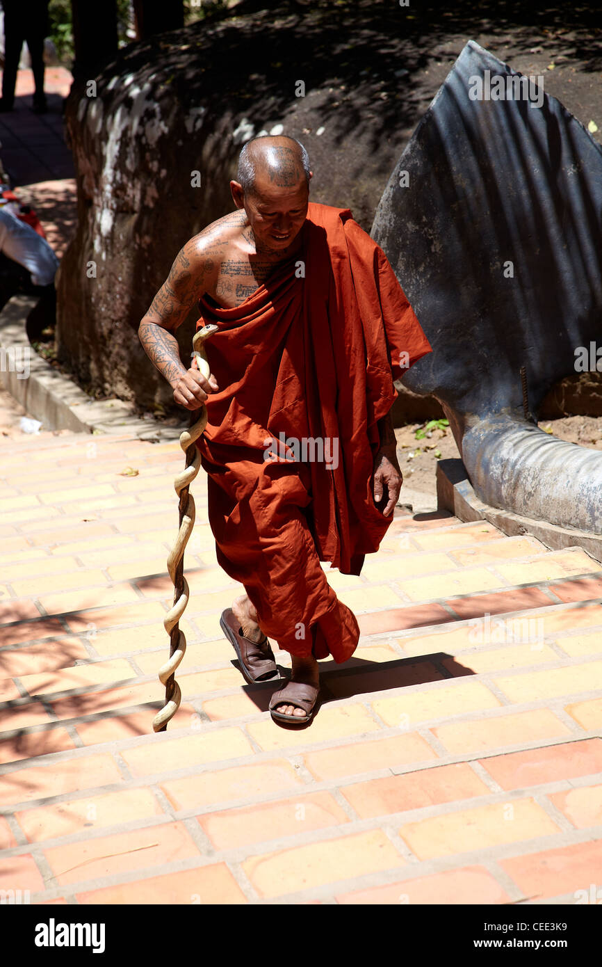 happy Buddhist monk climbing stairs in cambodia with walking stick ...