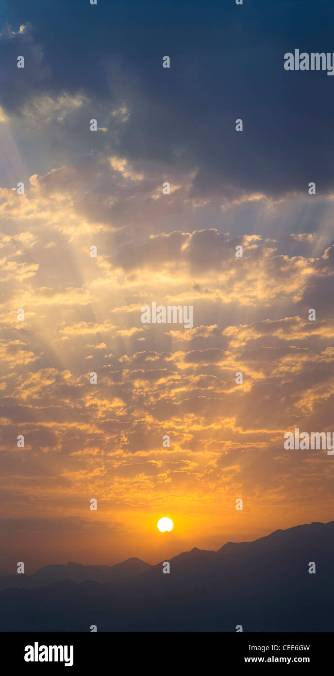The Sun rising over mountains Stock Photo - Alamy