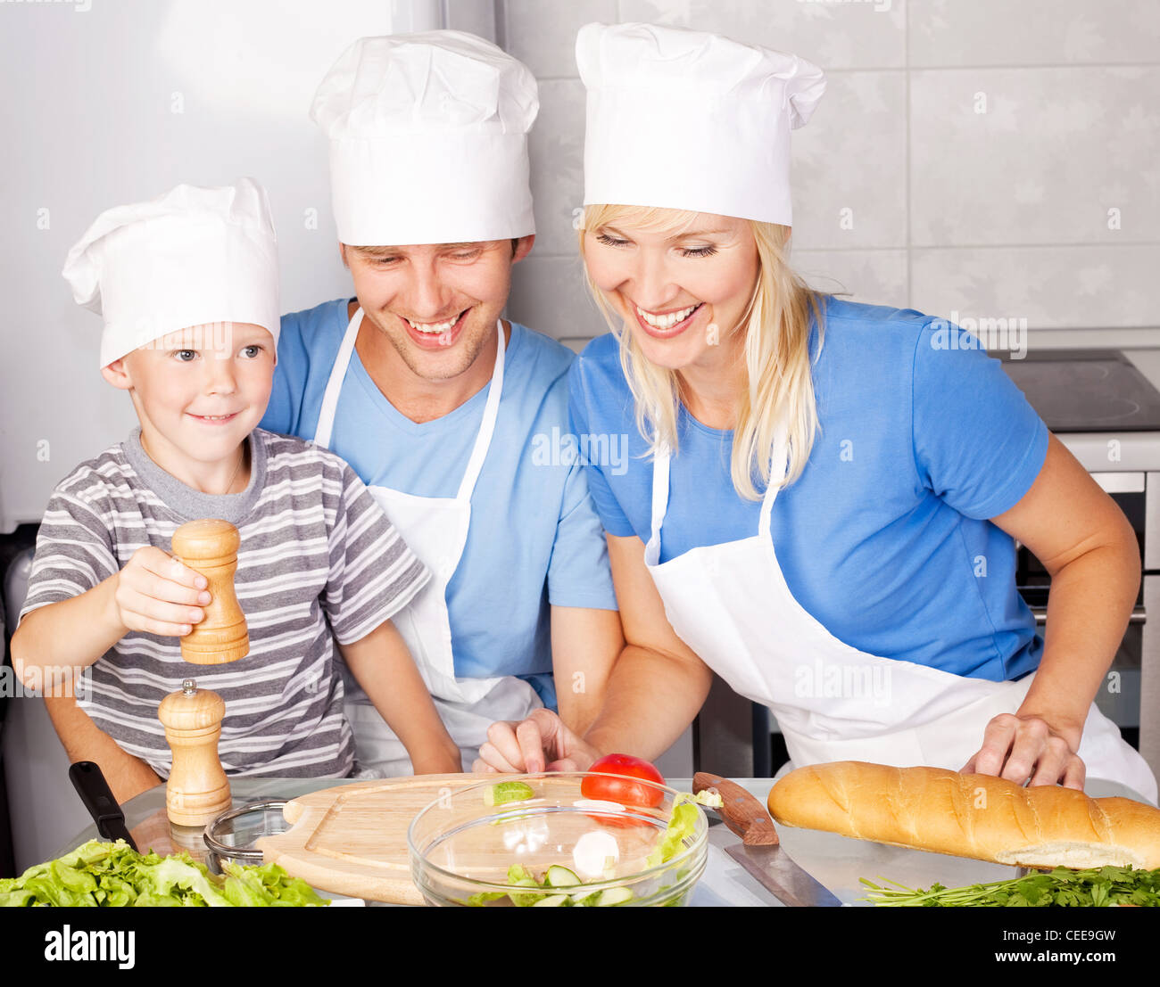 young family; father, mother and their five year old son cook together ...
