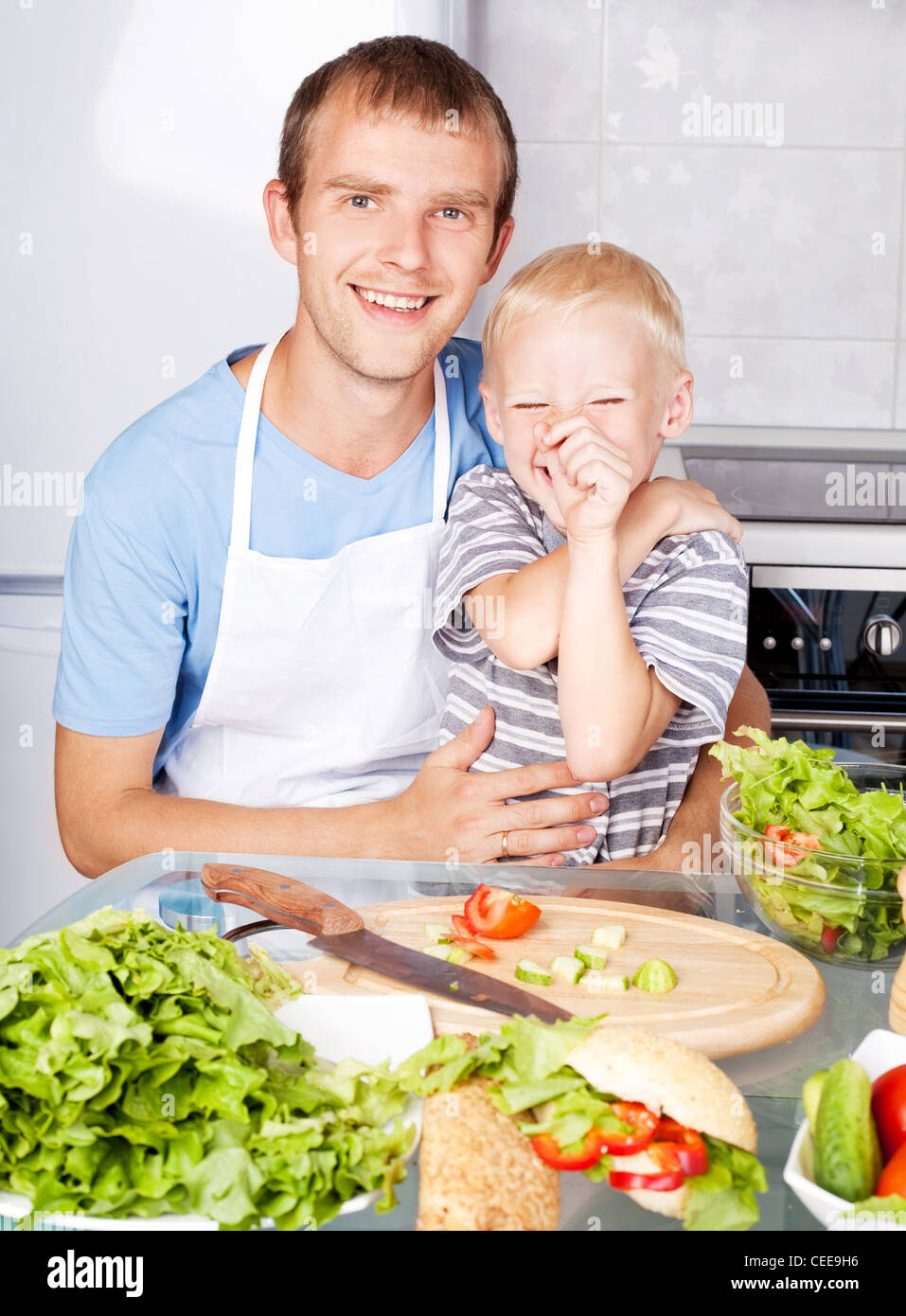 young father and his five year old son cook together in the kitchen at ...