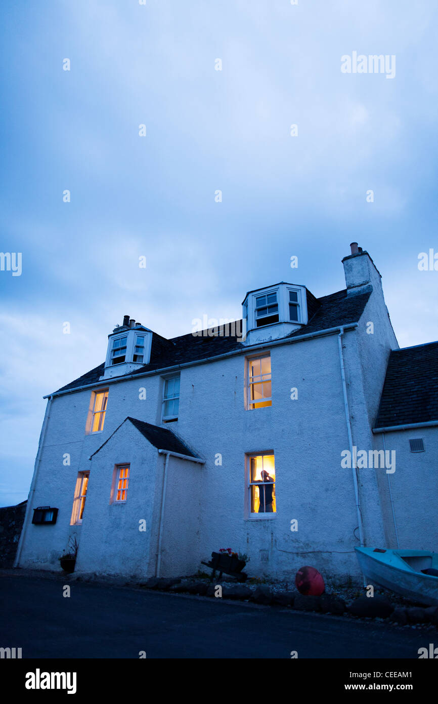 A man stands in the window looking out of the Gigha Hotel and pub at ...
