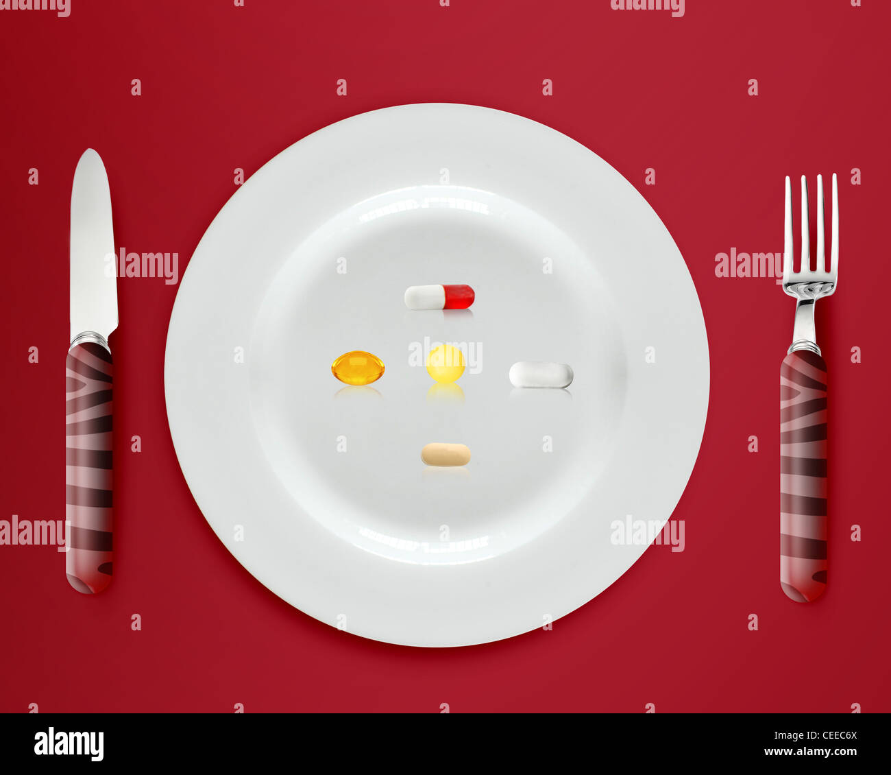 cutlery and plate with pills and capsules on red background Stock Photo ...