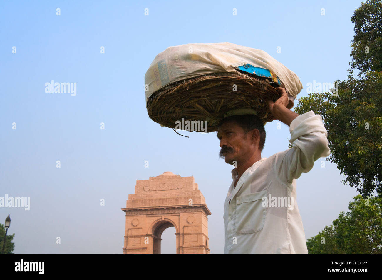 Indian man carrying basket on head, Indian Gate in the distance, Delhi ...