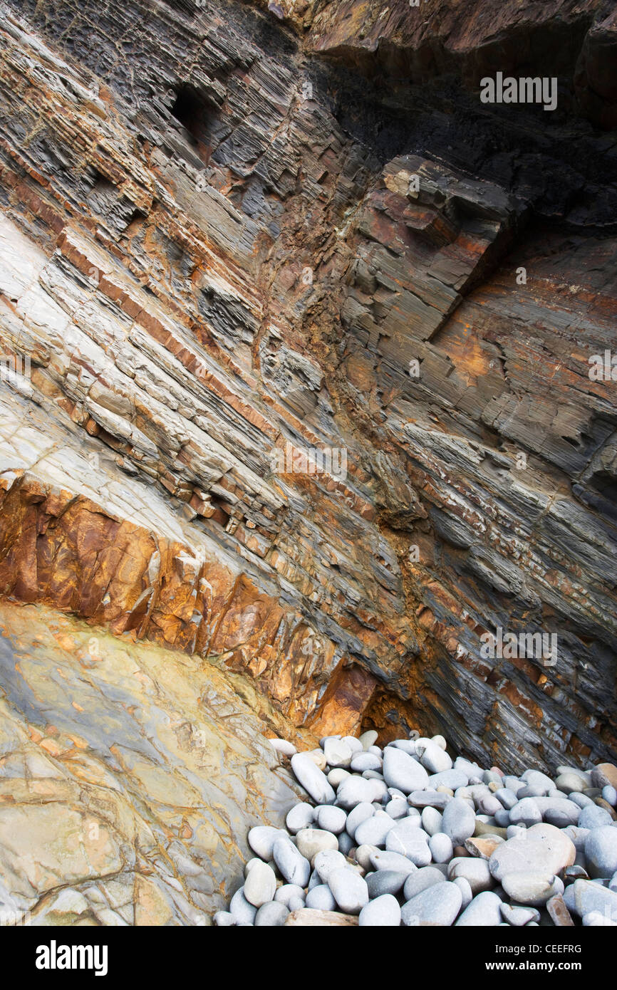 Close up of colourful rock strata at Sandymouth Beach. There is a pile ...