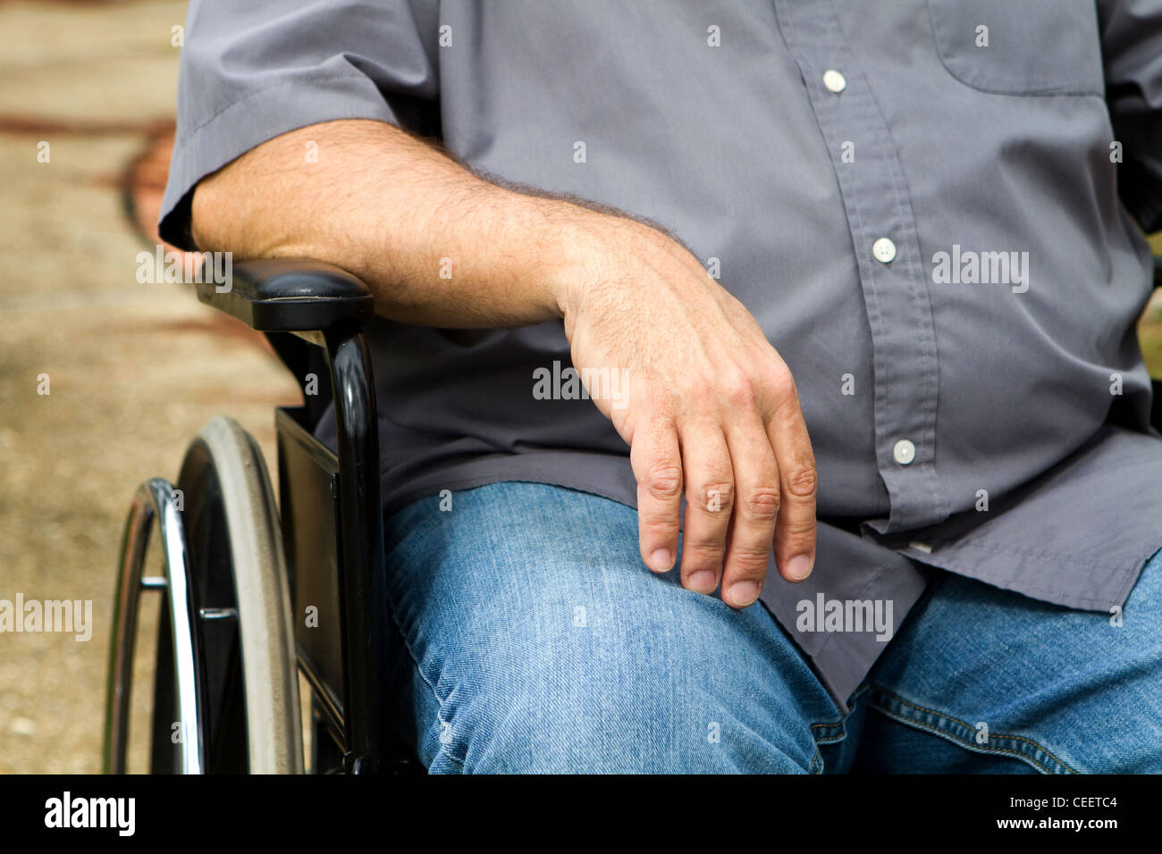 Close up of disabled man's arm and torso as he sits in a wheelchair ...
