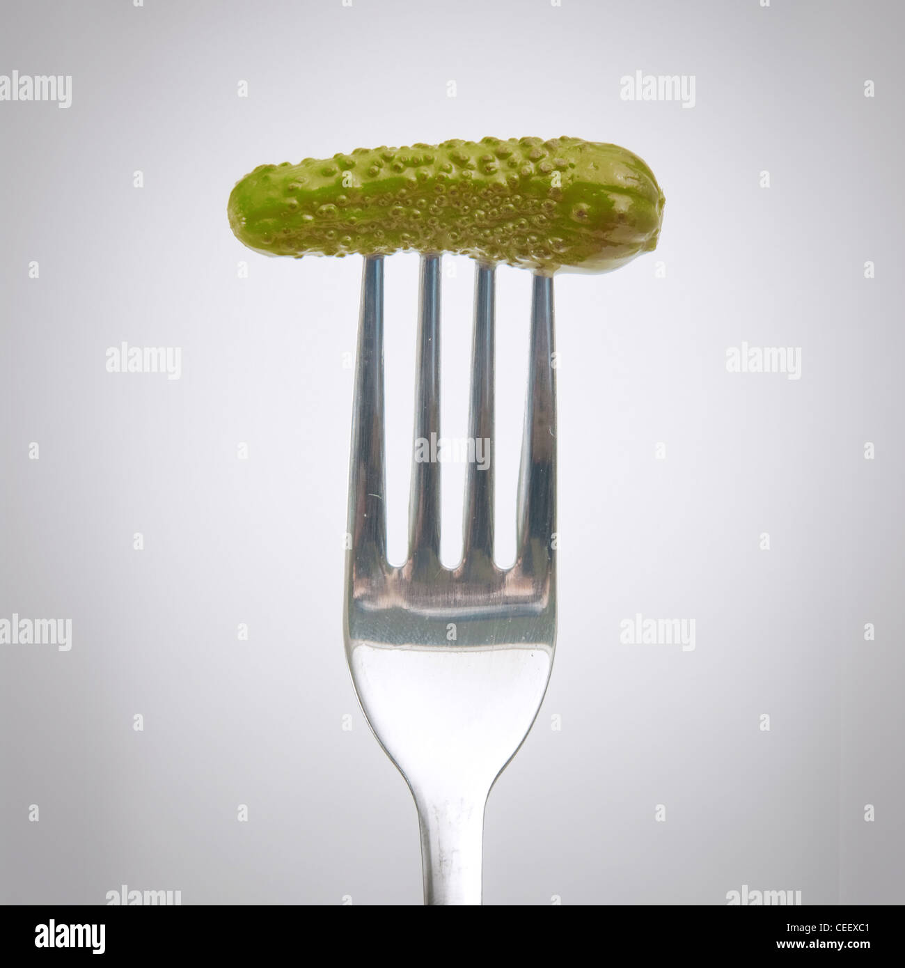 Small pickled green cucumber impaled on a silver fork Stock Photo - Alamy