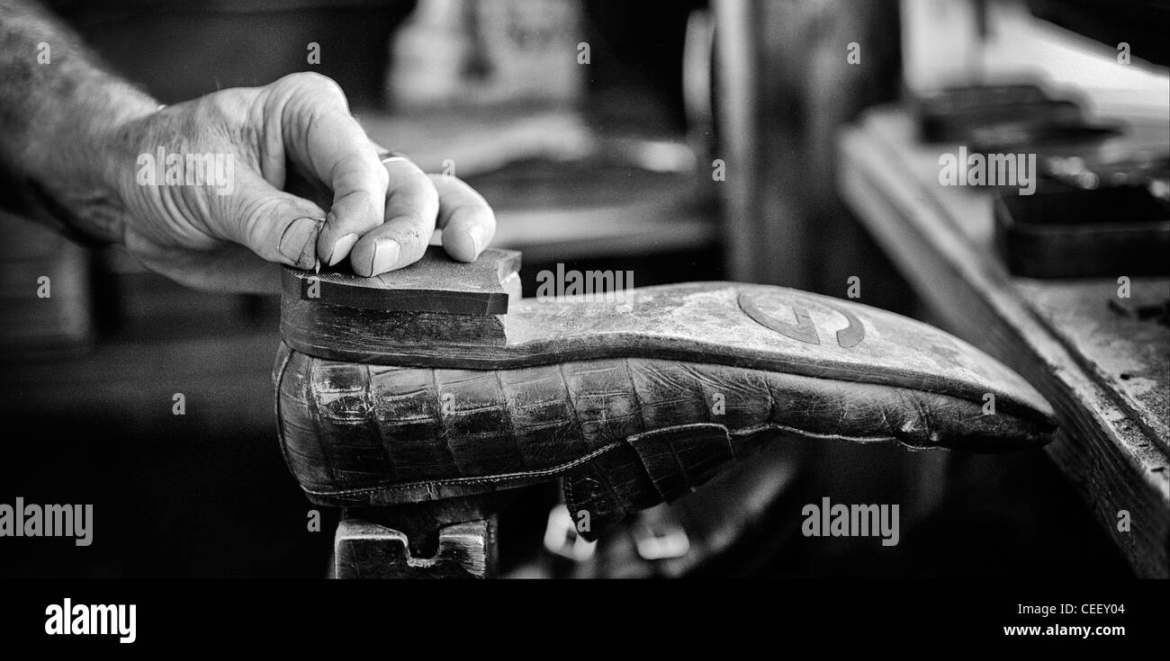 A shoemaker's hand positions a nail while repairing a shoe Stock Photo ...