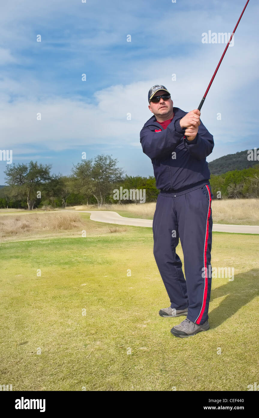 Male middle aged golf player in sweat suit after teeing off Stock Photo ...