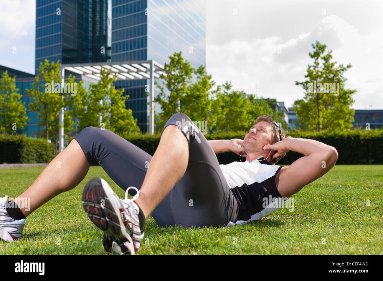 Urban sports - young man is doing warming up and sit-ups before running ...