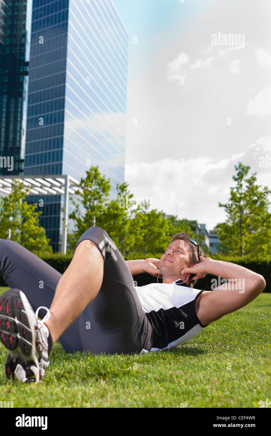 Urban sports - young man is doing warming up and sit-ups before running ...