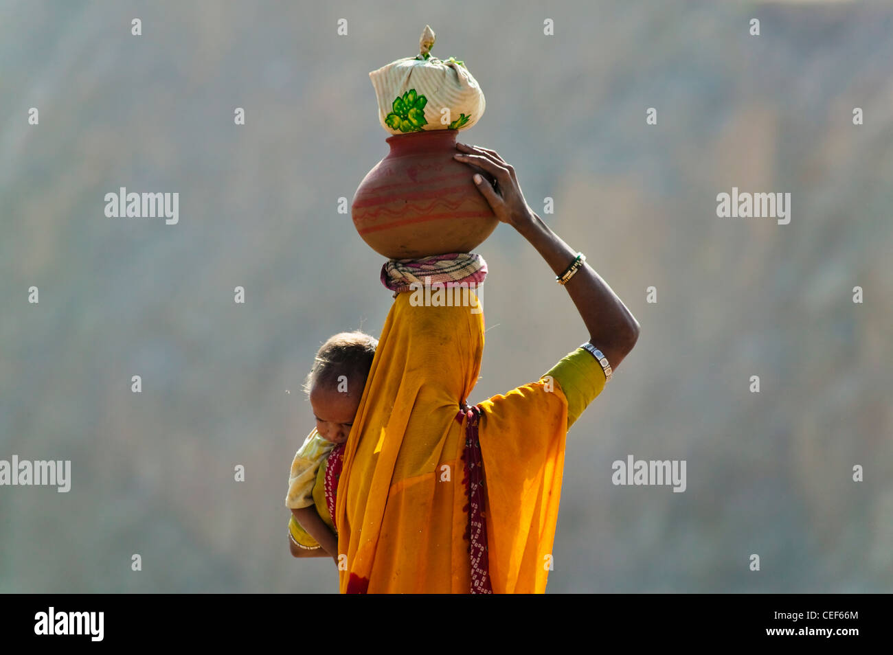 Village woman carrying baby and load on the head, Udaipur, Rajasthan ...