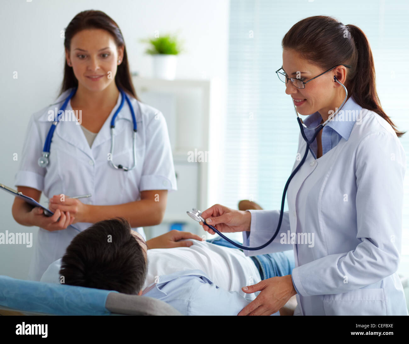 Portrait of two female doctors looking at patient during medical ...