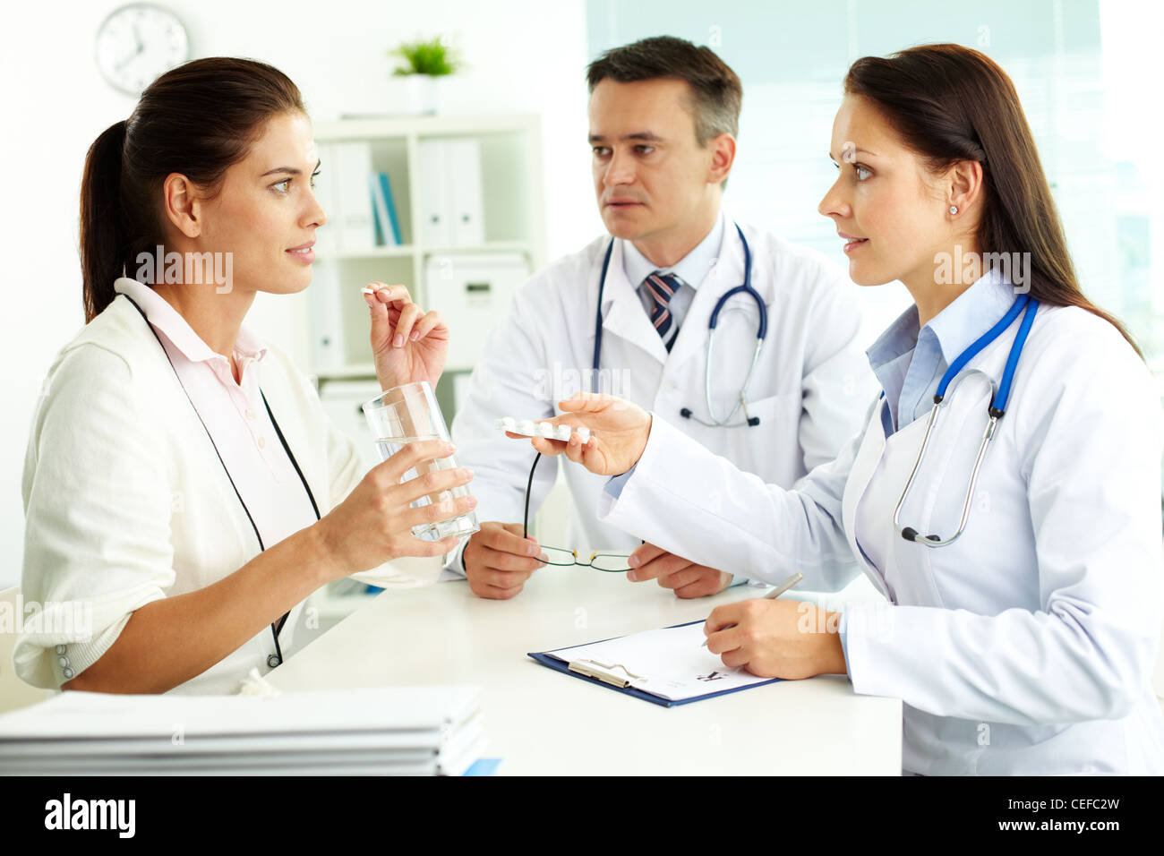 Portrait of confident practitioners prescribing tablets to patient in ...