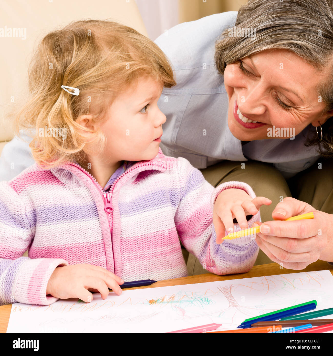 Grandmother and granddaughter drawing together with pencils at home ...