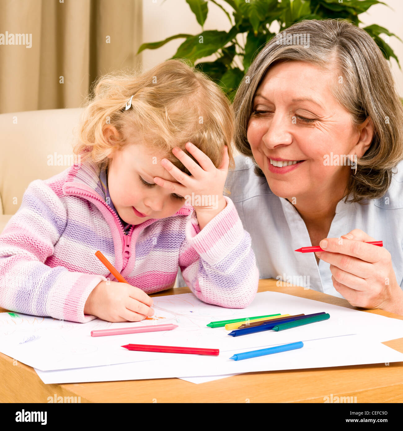 Grandmother and granddaughter drawing together with pencils at home ...