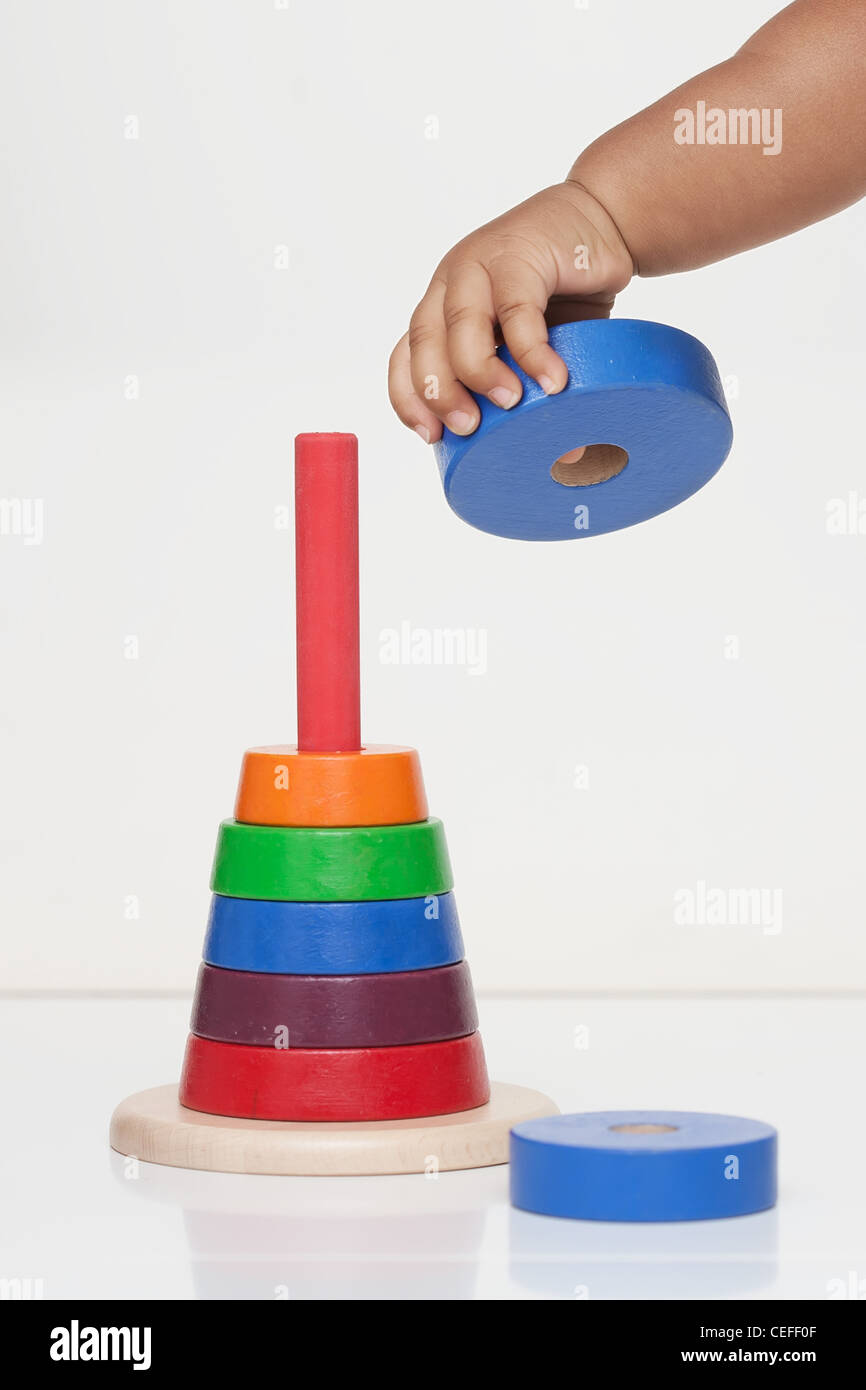 Baby's hand holding a wooden toy, demonstrating fine motor skill Stock ...