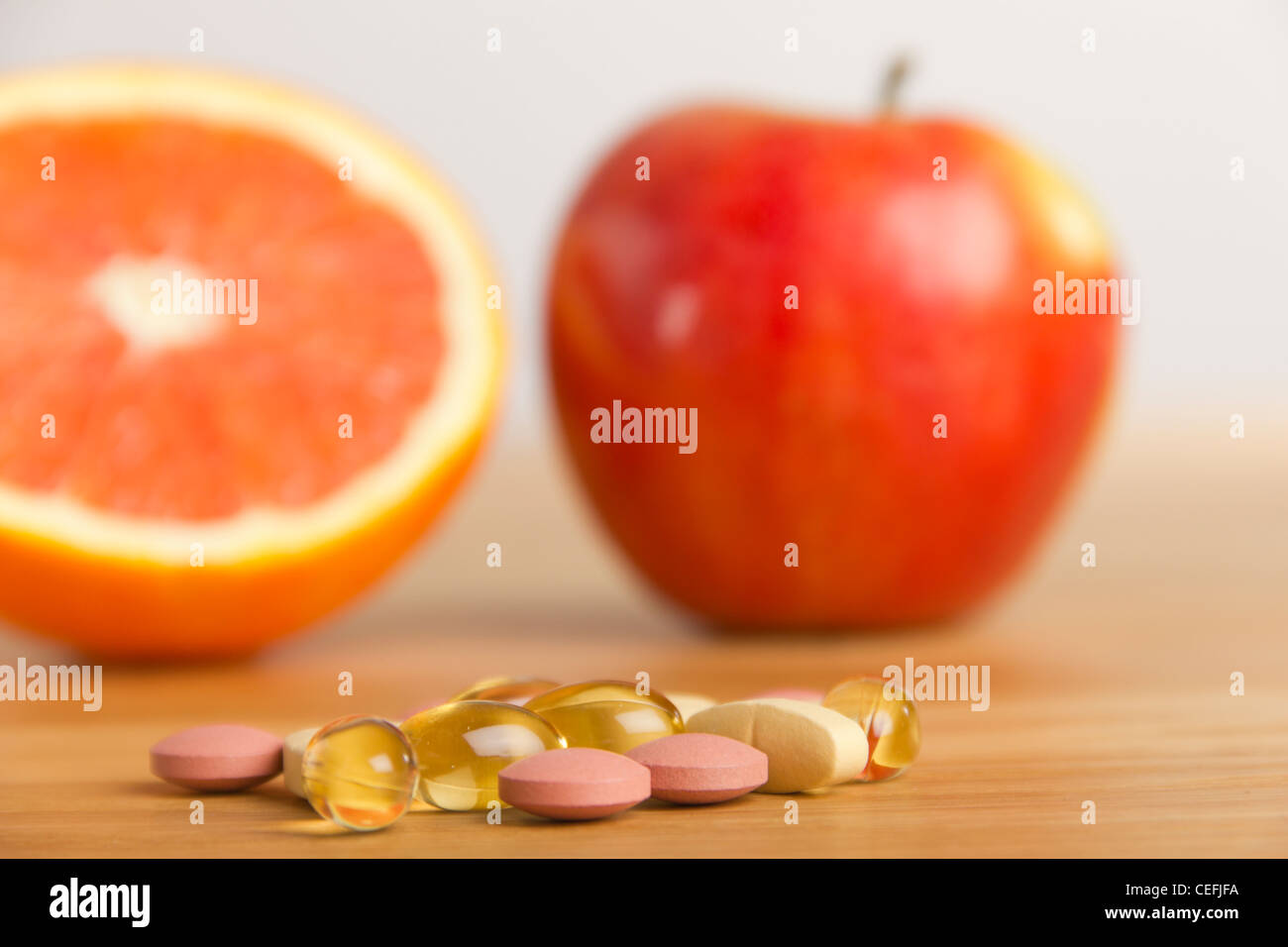 Dietary supplement in front of an apple and an orange Stock Photo - Alamy