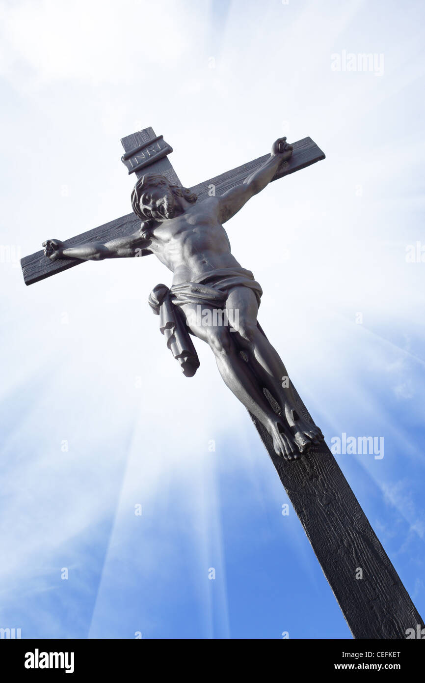 Jesus on the cross against a blue sky with glare Stock Photo - Alamy