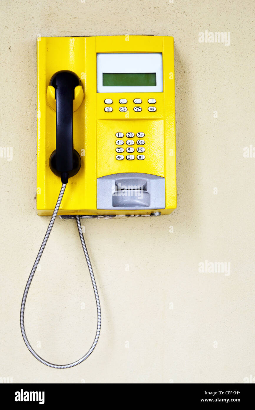 Yellow public telephone close-up on the wall Stock Photo - Alamy