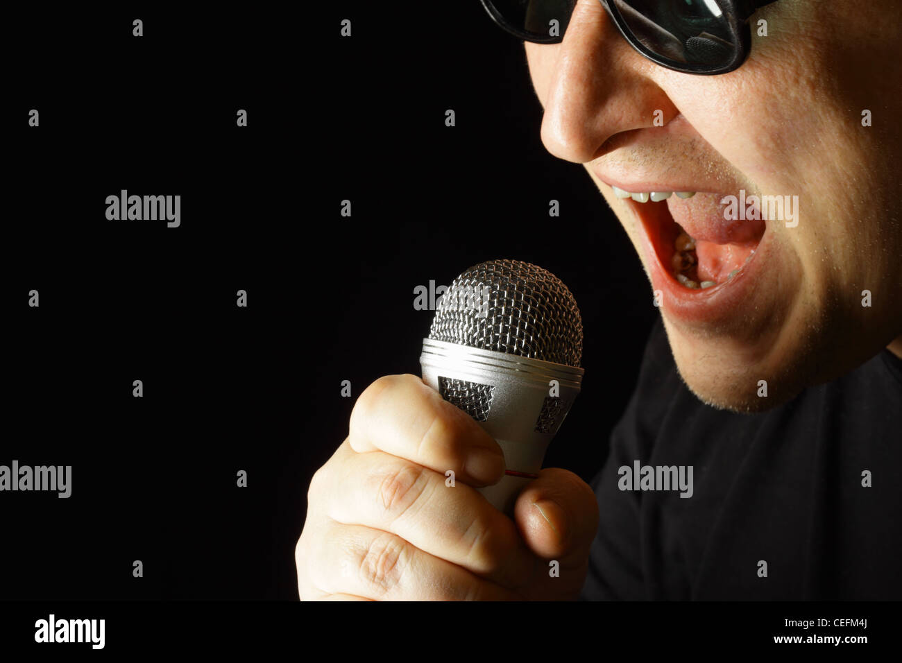 Performer with microphone over black background Stock Photo - Alamy