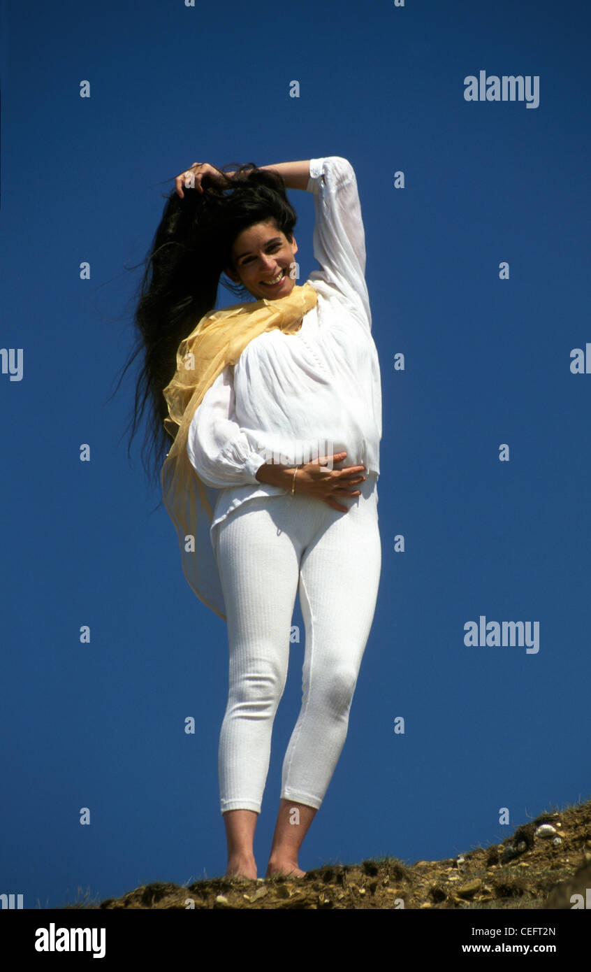 pregnant anglo asian woman standing against blue sky Stock Photo - Alamy