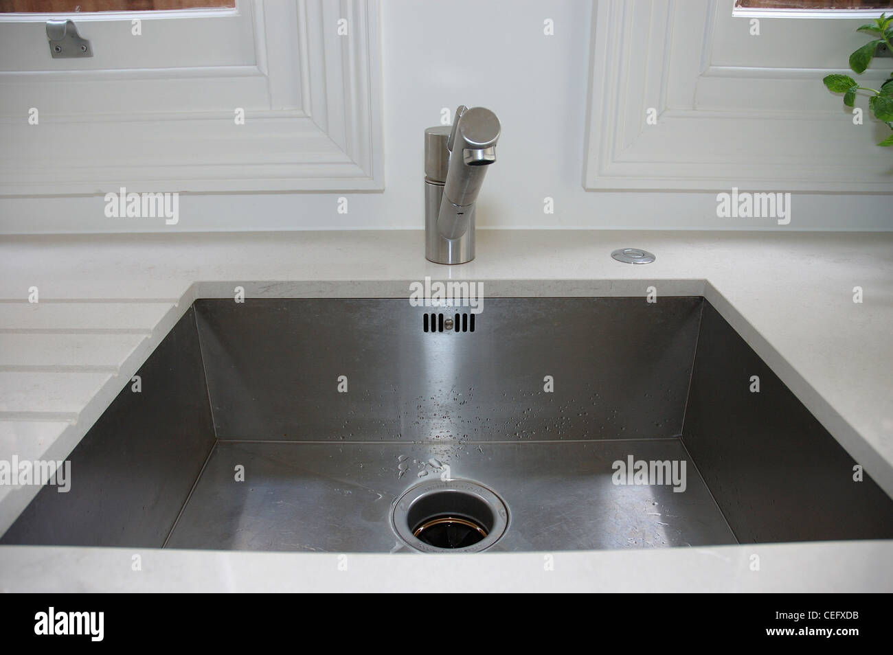 Close up of stainless steel tap above under-set stainless steel sink ...