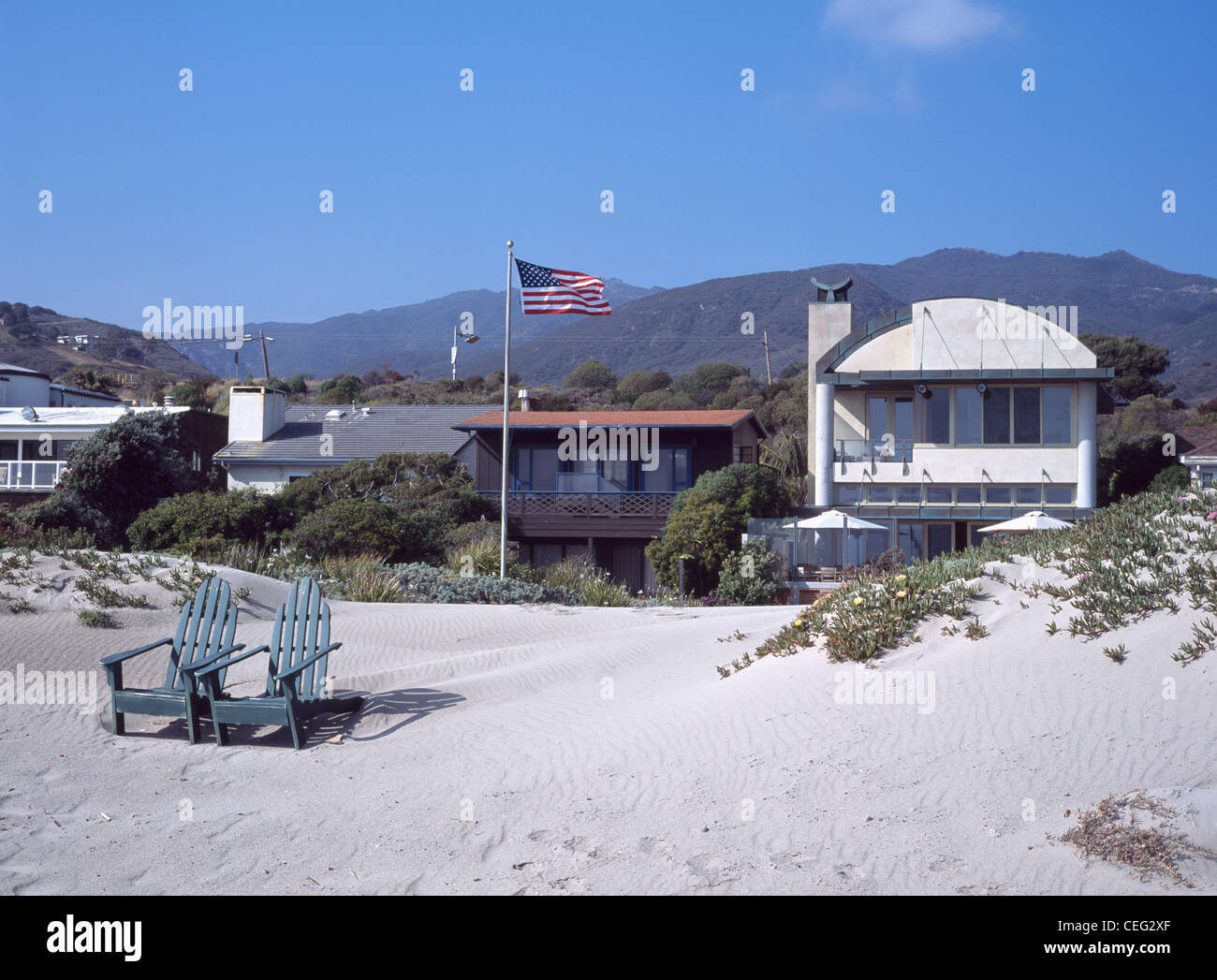 Adirondack chairs on sand in front of modern beach side house Stock ...
