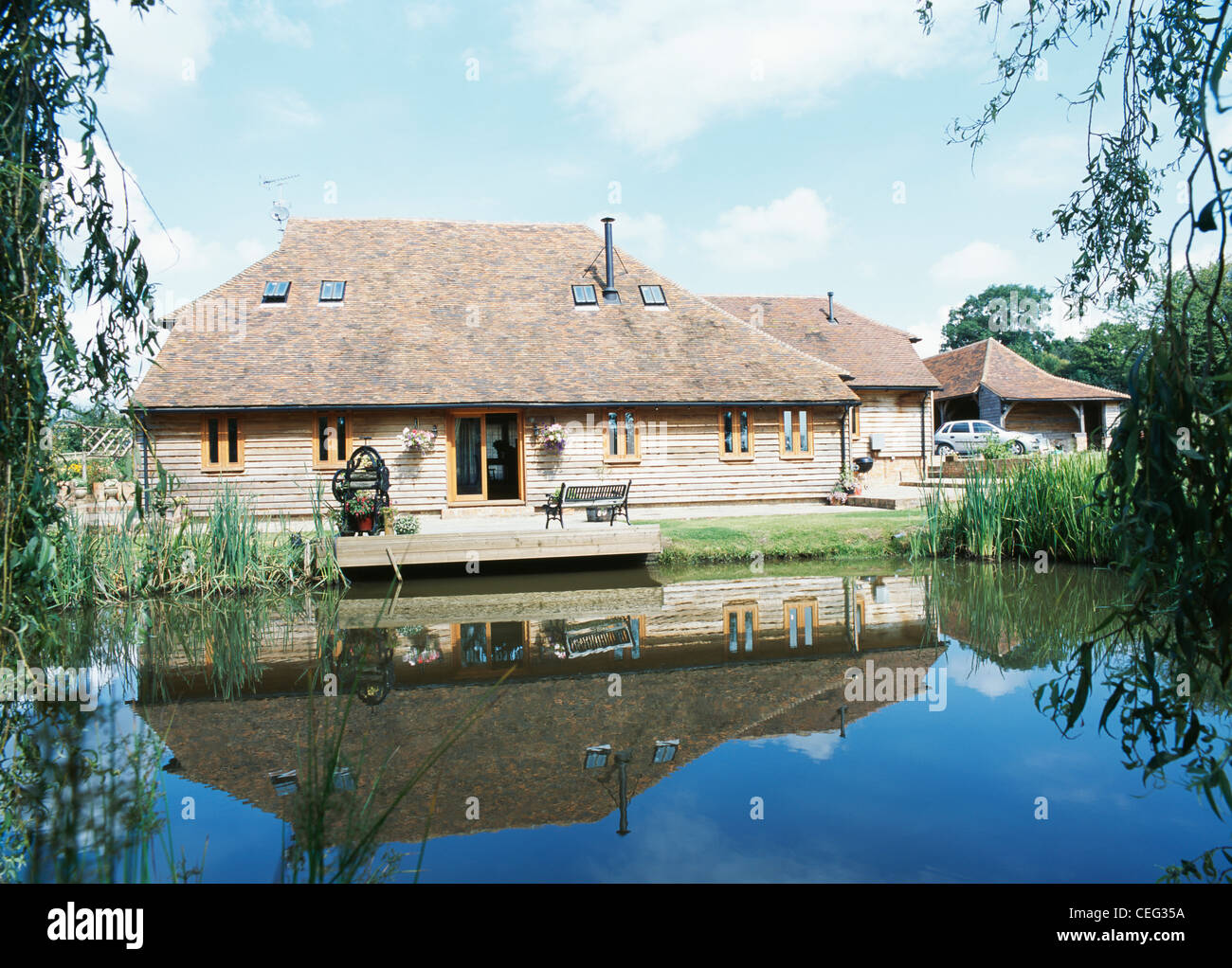 Large pond in front of traditional wooden barn conversion with timbered ...