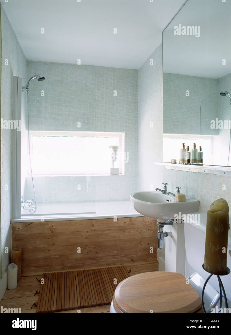 Shower above wood paneled bath in modern white bathroom with large ...