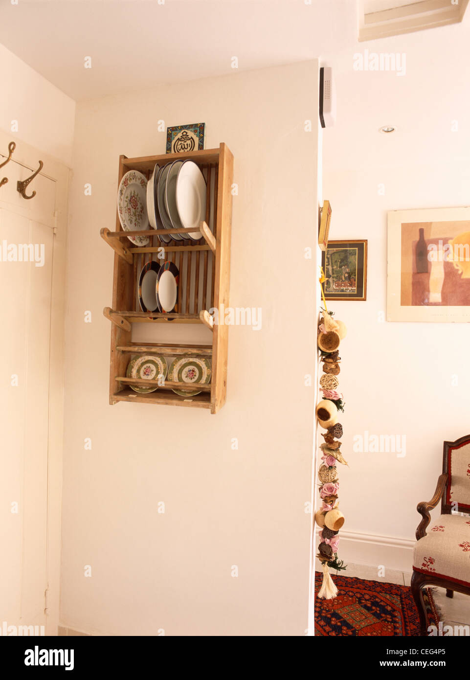 Small pine plate-rack on wall of white cottage dining room with garland ...