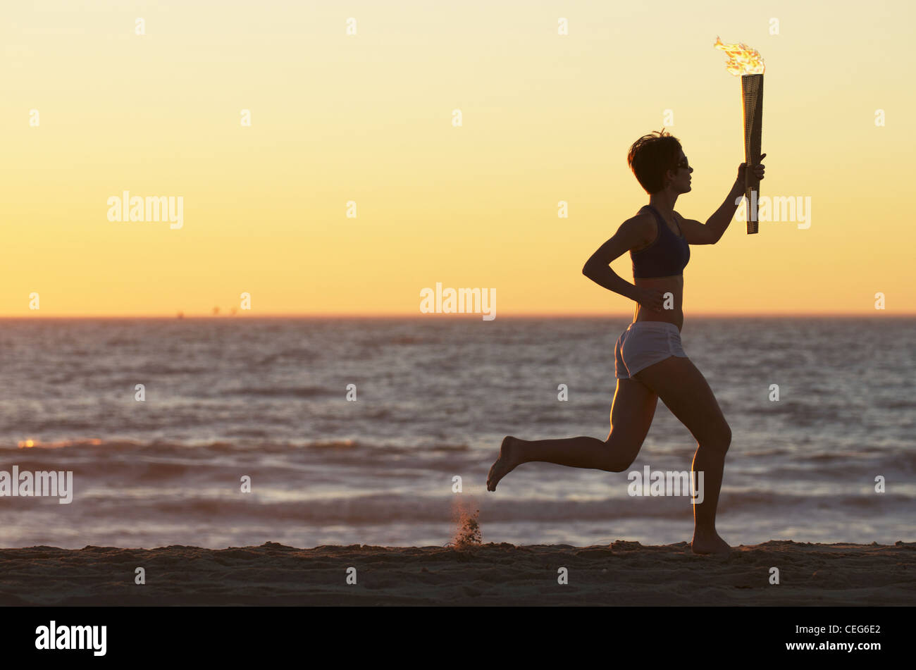 A woman running on the beach with a simulated olympic relay torch Stock ...