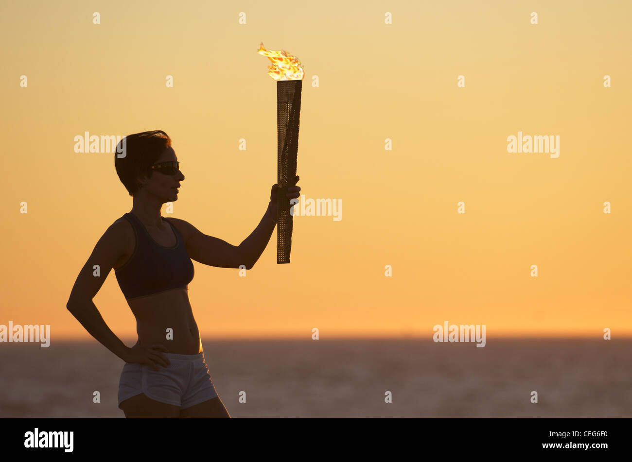 A portrait of a silhouetted woman holding a simulated olympics relay ...