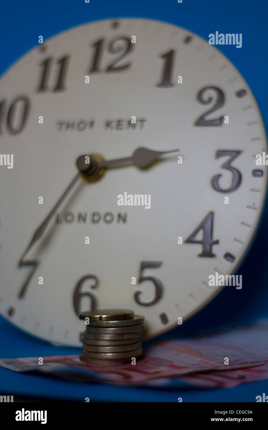 An old-fashioned analogue clock on a blue background with a pile of ...
