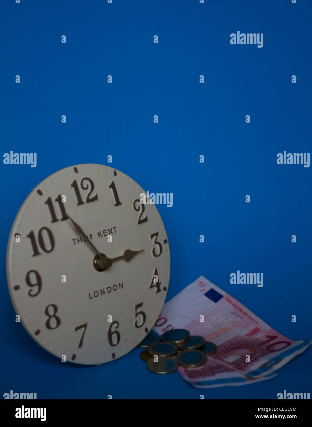 An old-fashioned analogue clock on a blue background with a pile of ...
