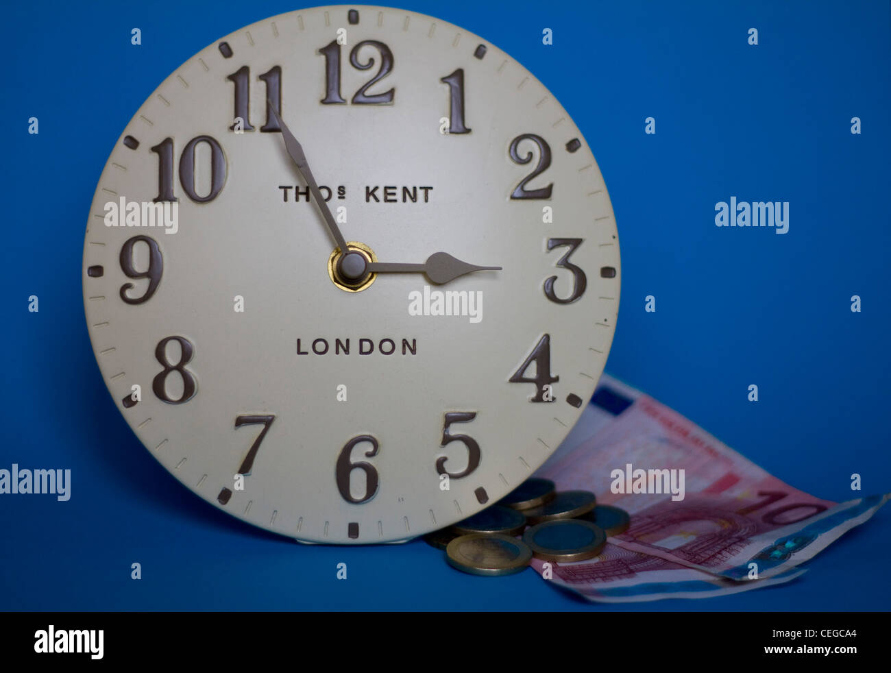 An old-fashioned analogue clock on a blue background with a pile of ...