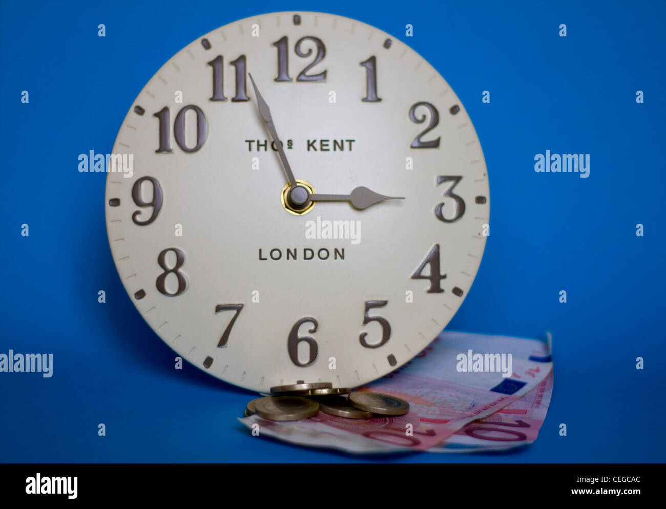 An old-fashioned analogue clock on a blue background with a pile of ...