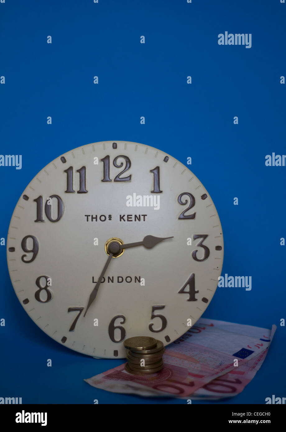 An old-fashioned analogue clock on a blue background with a pile of ...