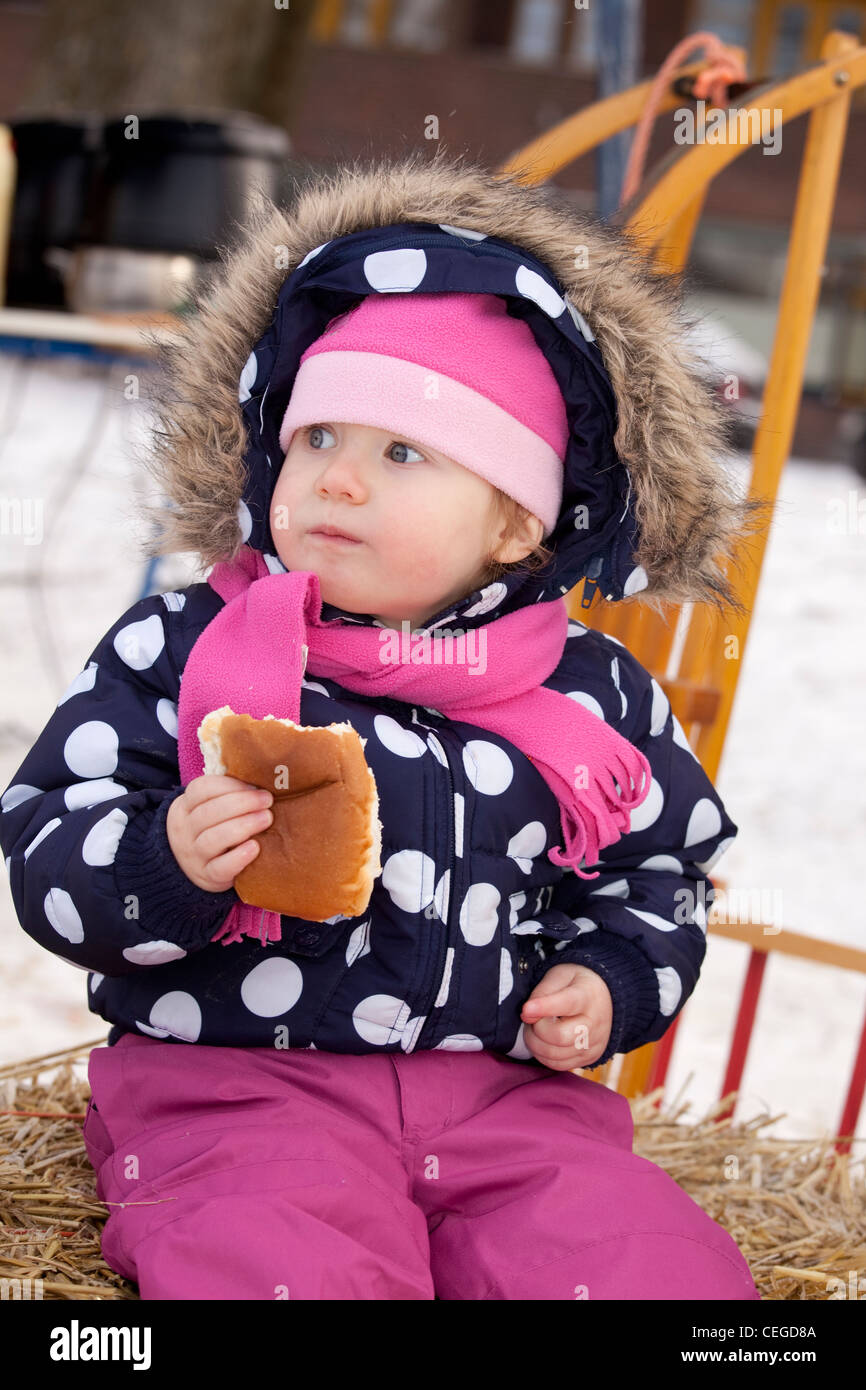 Adorable toddler in winter clothing eating Stock Photo - Alamy