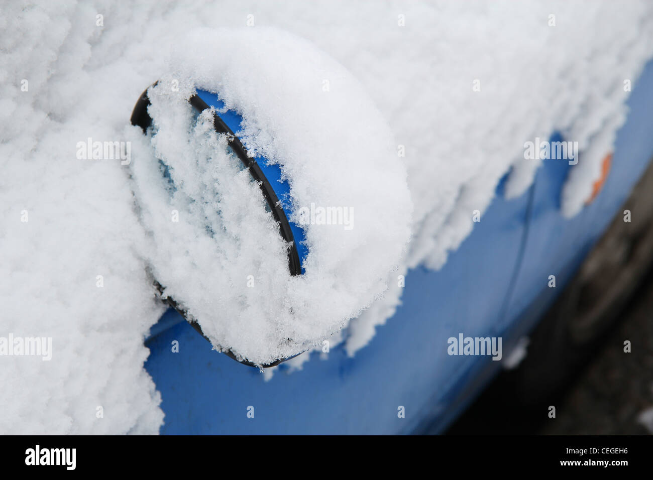 blue car covered in snow. Detail of side mirror with snow covering the ...