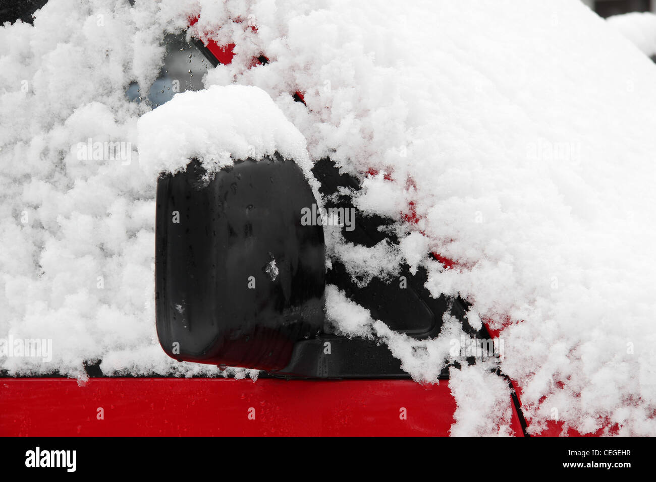 red car covered in snow. Detail of side mirror and window covered in ...