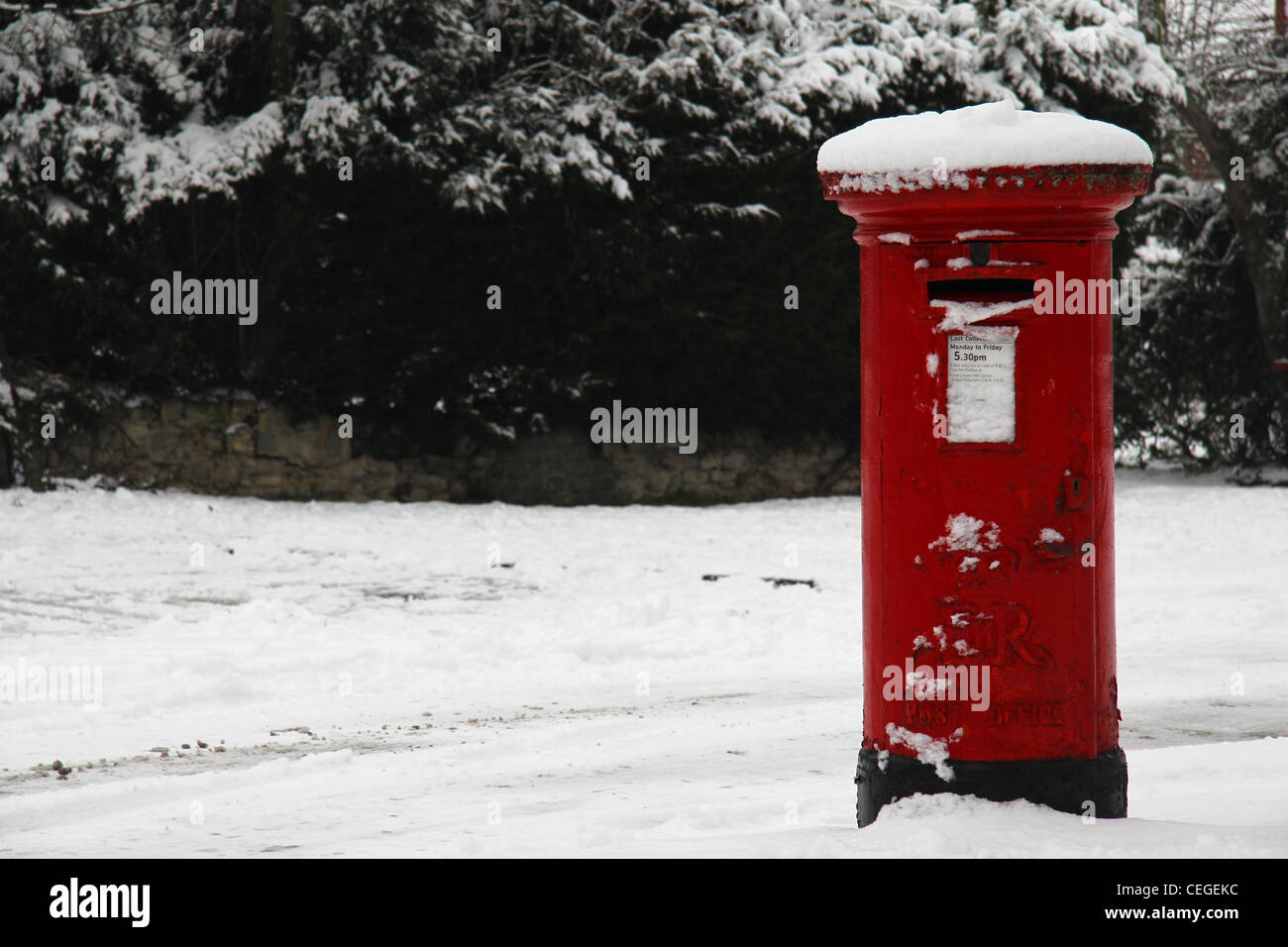 red mail box in street covered in fresh snow in a grey day with dull ...