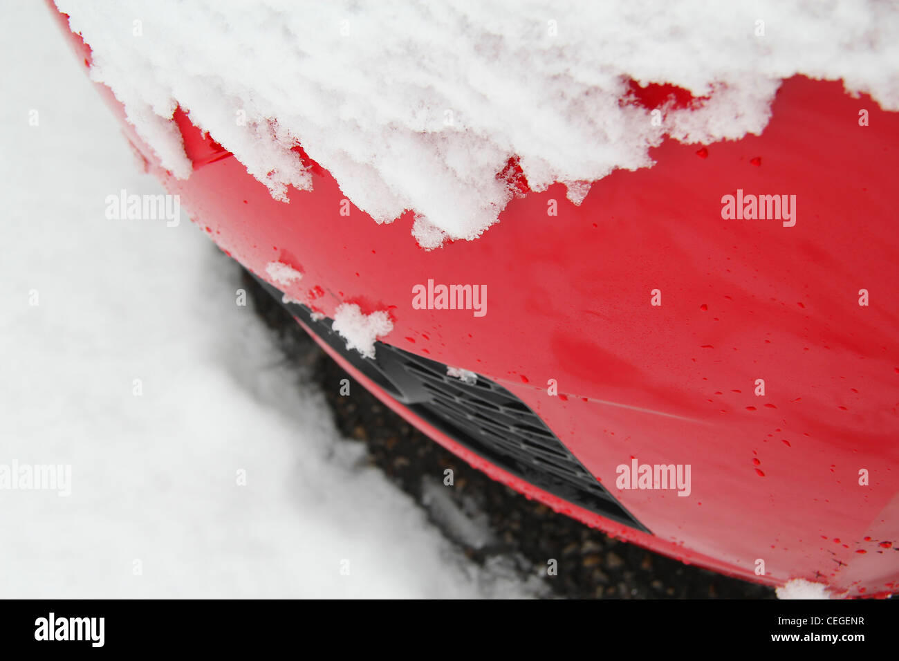 close up of bumper detail of red car covered in snow seen from above ...
