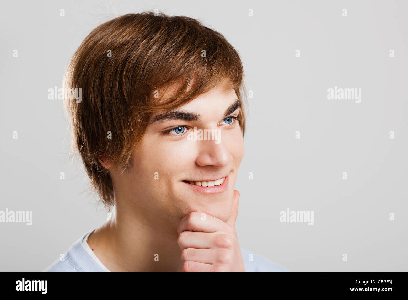 Portrait of a handsome and happy young man thinking, over a gray ...